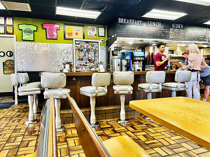 The counter seating offers front-row tickets to the culinary show, with colorful t-shirt art providing the perfect backdrop.