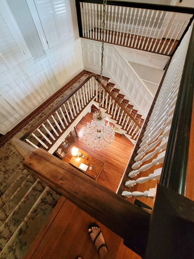 A staircase grand enough to make any entrance memorable. That chandelier dangling through the center has illuminated countless special moments in this historic home.