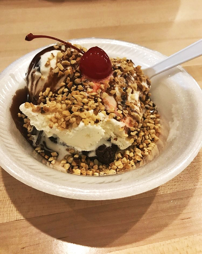 This sundae isn't just dessert, it's performance art&mdash;hot fudge cascading over ice cream hills, crowned with nuts and a cherry sentinel.