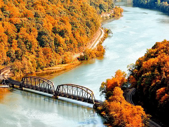 Autumn paints the Greenbrier Valley in impossible oranges and golds, with the river cutting through like a blue ribbon on nature's perfect gift.