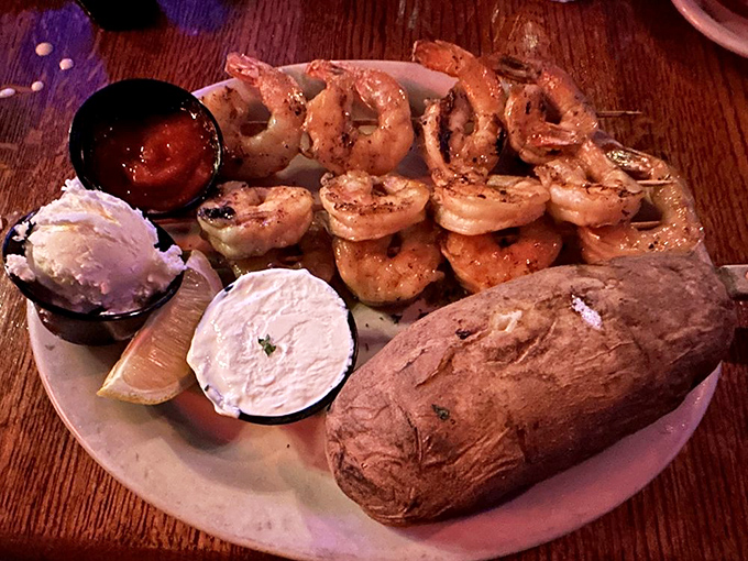Char-grilled shrimp arrive like savory soldiers on a plate, flanked by their allies: a perfect baked potato and the traditional condiment brigade.