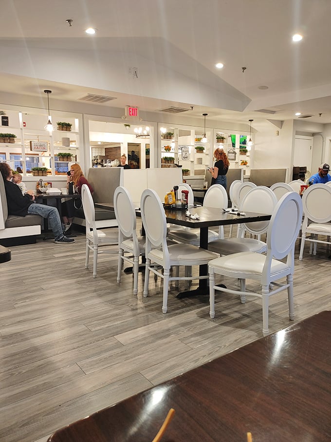 White chairs against light wood floors create a bright, airy dining space where breakfast dreams come true and diet plans go to die.