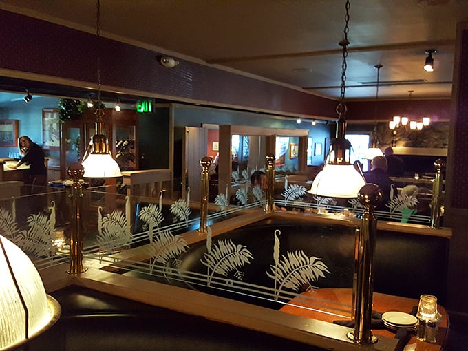 Brass railings and etched glass dividers create intimate dining zones where your conversation feels like the only one in the room.