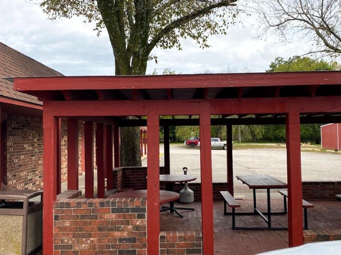 The outdoor dining area where summer evenings feel magical. Picnic tables under the shade where strangers become neighbors over shared chicken appreciation.