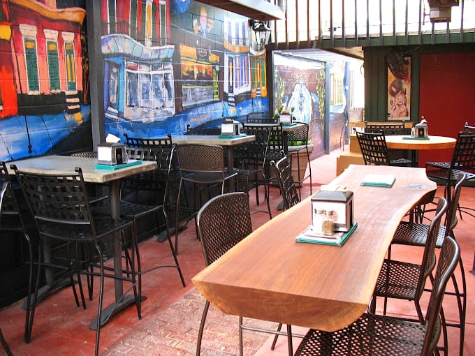 This outdoor seating area isn't just a patio&mdash;it's an urban oasis where murals tell stories while tables patiently await their next food-loving guests.