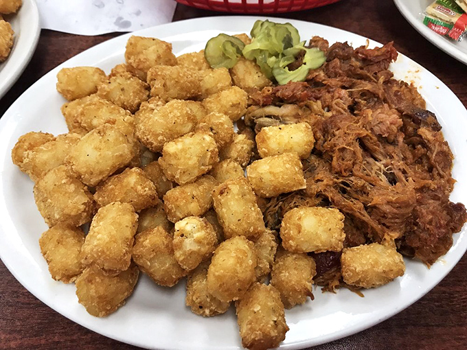Pulled pork and tater tots share plate space like old friends at a reunion, with pickle chips adding that perfect tangy counterpoint.
