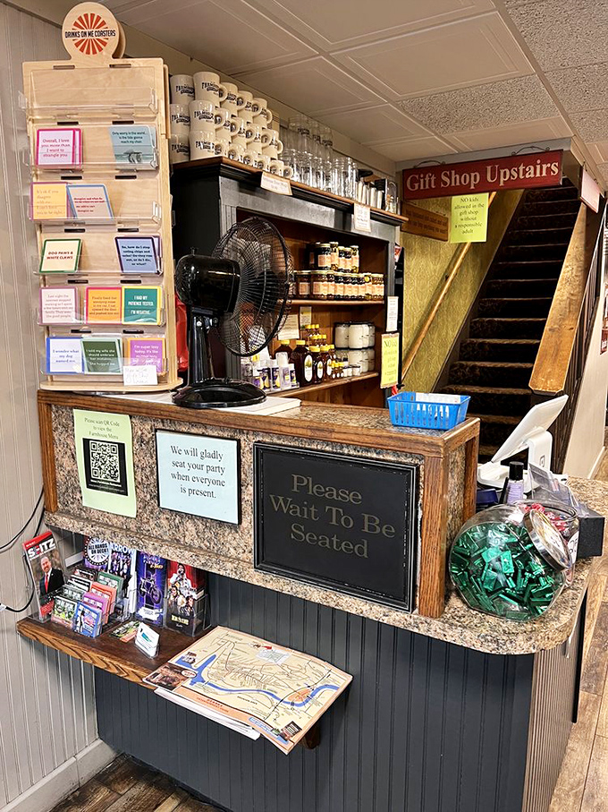 The hostess stand—gateway to comfort food paradise—complete with mugs for regulars and a gentle reminder to wait your turn for greatness.