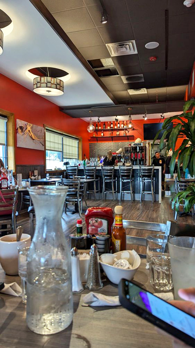 The vibrant orange walls and thoughtful lighting create an energetic backdrop for the morning ritual of coffee and conversation.