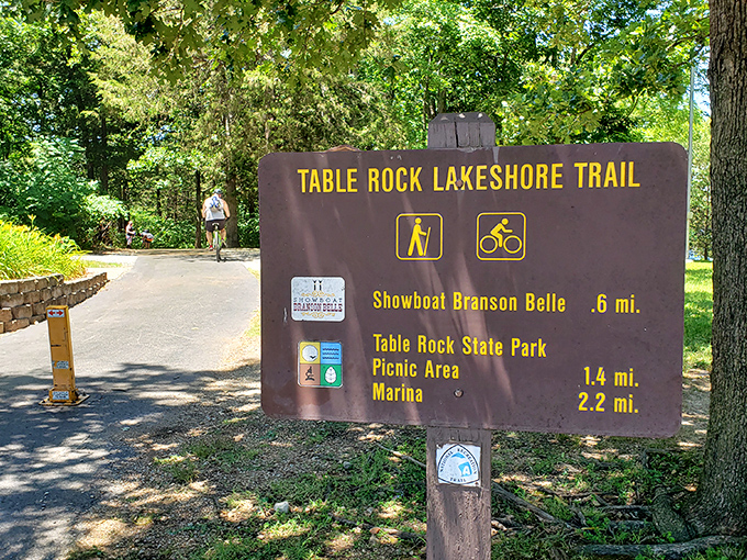 Summer's lush canopy frames the trailhead sign perfectly. That cyclist knows what we're all thinking: paradise isn't always a tropical beach&mdash;sometimes it's right here in Missouri.