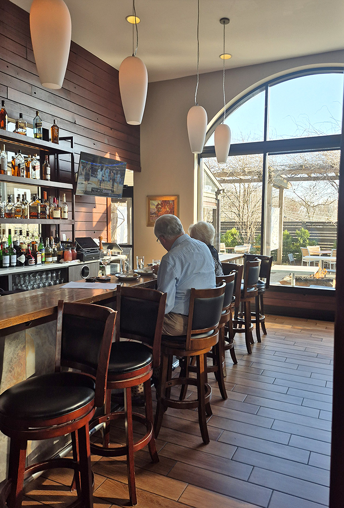 The bar area strikes that perfect balance—welcoming enough for regulars, sophisticated enough for special occasions. Notice the sunlight pouring through those windows.