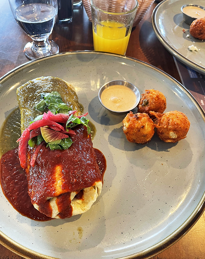 This isn't just a burrito, it's a flavor fiesta wrapped in a tortilla, smothered in rich sauce and accompanied by crispy golden spheres of potato goodness.