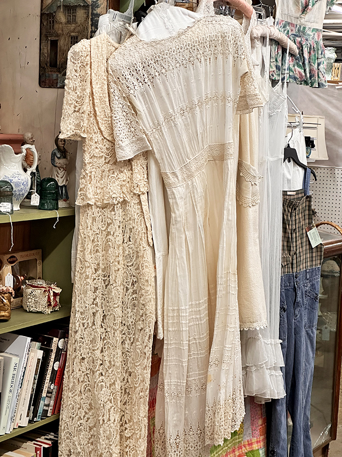Delicate vintage dresses hang like ghosts of celebrations past. The intricate lacework represents countless hours of craftsmanship we rarely see in modern clothing.