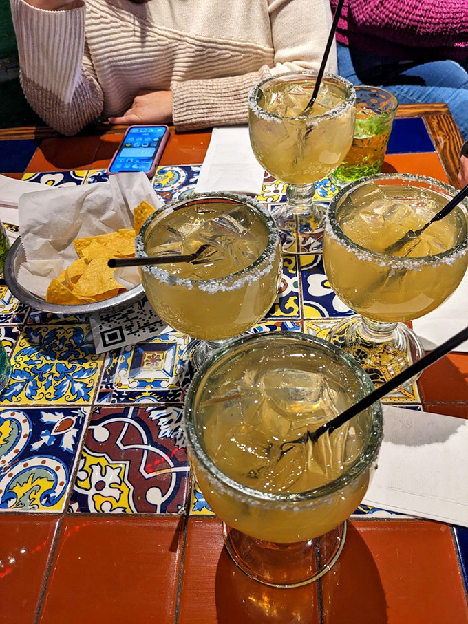 Margaritas with salt-crusted rims, sitting pretty on those colorful tiles like they're on vacation themselves. The chips are just waiting to join the party.