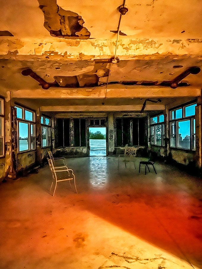 Sunlight creates an eerie glow in this former patient room, where shadows dance across decaying walls that have heard too many final breaths. 