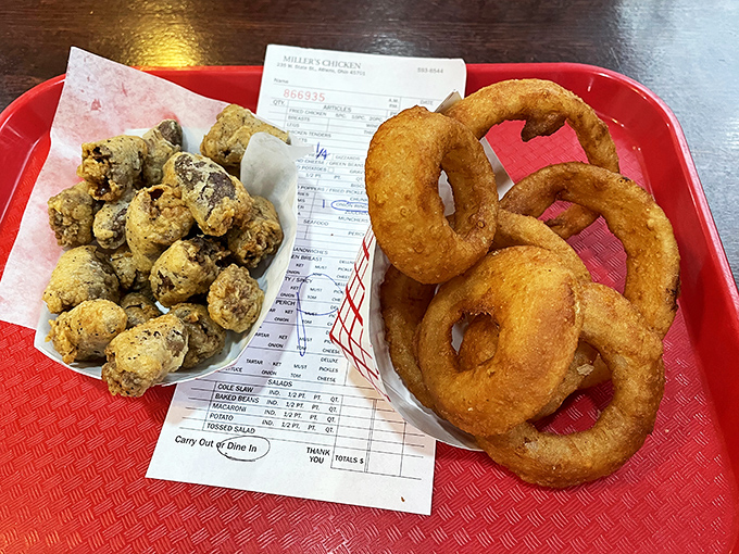 On one side, golden onion rings with their perfect crunch; on the other, fried mushrooms. This red tray holds the supporting cast to chicken's starring role.