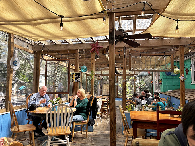 The screened porch dining area feels like eating in a treehouse for grown-ups, where string lights and gentle breezes enhance every bite.
