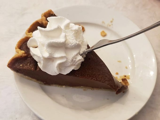 Chocolate pie with a cloud of whipped cream—the kind of dessert that makes you consider ordering a second slice before finishing the first.