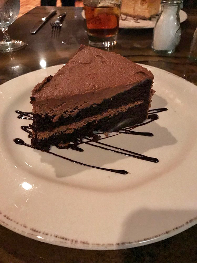 A slice of chocolate cake so rich it should have its own tax bracket, with layers that tell a more compelling story than most Hollywood sequels.