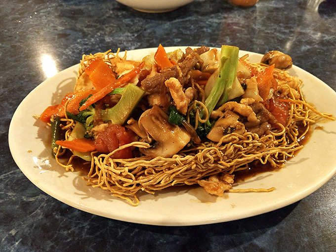 Crispy noodles cradle stir-fried vegetables and meat in a textural wonderland that makes every bite a delightful crunch-then-melt experience.