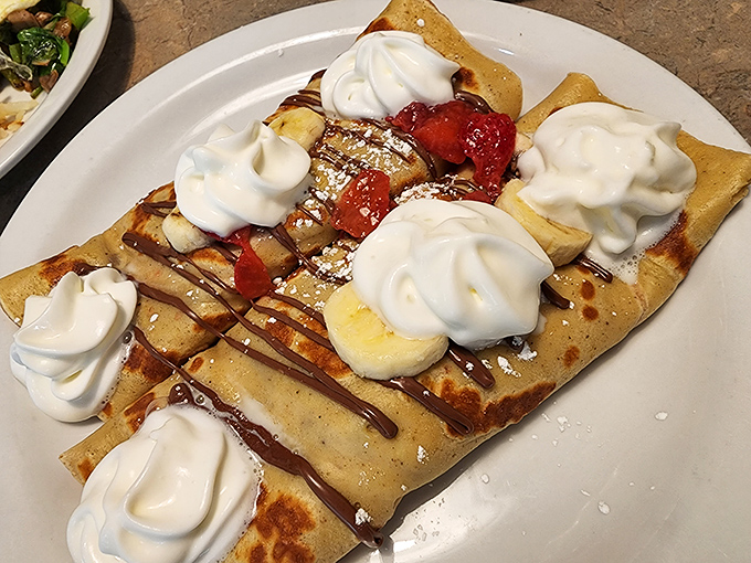 Dessert masquerading as breakfast &ndash; these delicate crepes adorned with fresh fruit, chocolate drizzle, and clouds of whipped cream make morning feel like a celebration.