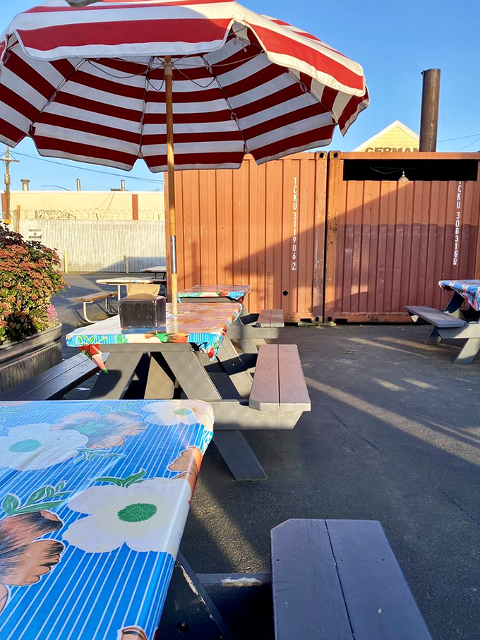 Picnic tables under a striped umbrella offer the perfect outdoor setting for enjoying smoky treasures. Because barbecue tastes even better with fresh air.
