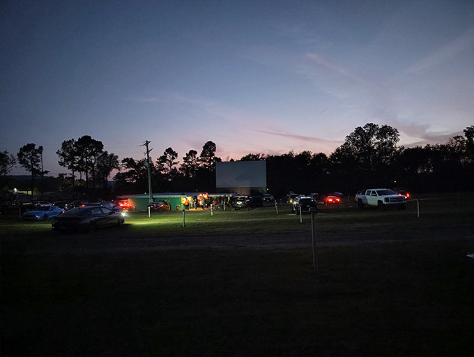 As darkness falls, headlights illuminate the path to concessions while the screen awaits its moment to shine.