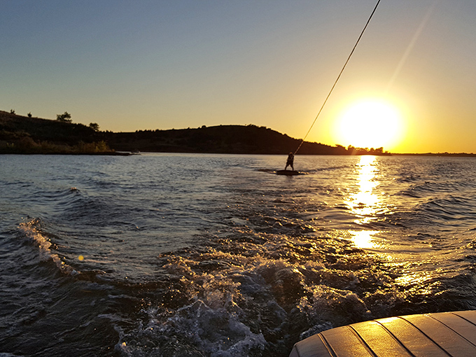 Sunset water skiing – that magical moment when the day's last light turns the reservoir into liquid gold. Pure Kansas magic.