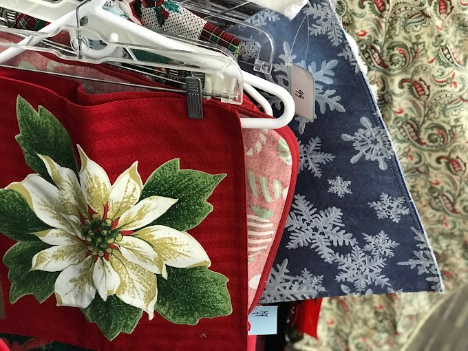 Holiday linens and textiles hang like festive flags, signaling that someone's Christmas table is about to get a budget-friendly makeover.