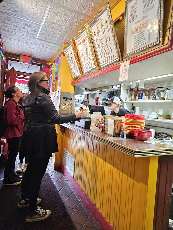 The counter where dreams come true. This is the stage where the hot dog magic happens, with gold-framed menus setting expectations high.