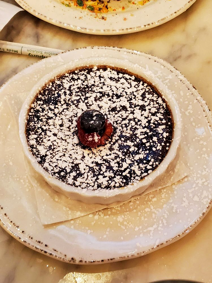 This isn't just dessert; it's performance art with a crisp sugar shell protecting creamy treasure below. That berry on top is the mic drop.