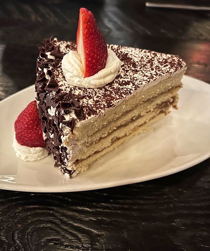 Layers of cake, cream, and chocolate topped with a strawberry sentinel. The kind of dessert that makes you reconsider the concept of "too full."
