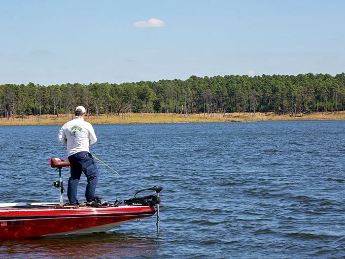 A lone angler casts into McGee Creek Reservoir's blue waters, practicing the ancient art of patience with modern equipment.