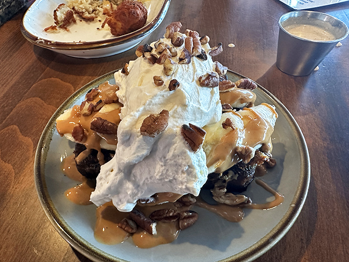 A mountain of French toast that would make Everest jealous, crowned with whipped cream and pecans—dessert masquerading as breakfast, and we're here for it.
