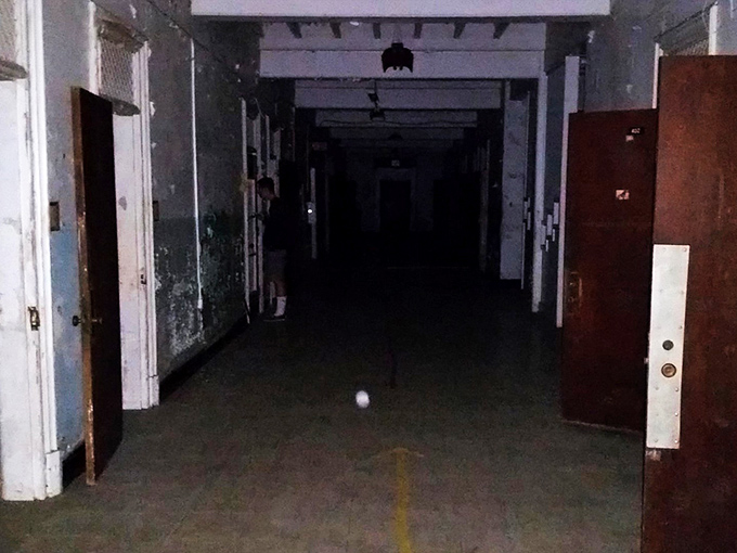 The Trans-Allegheny Lunatic Asylum's imposing fa&ccedil;ade and clock tower stand against a clear sky, architectural grandeur masking the complex human stories contained within.