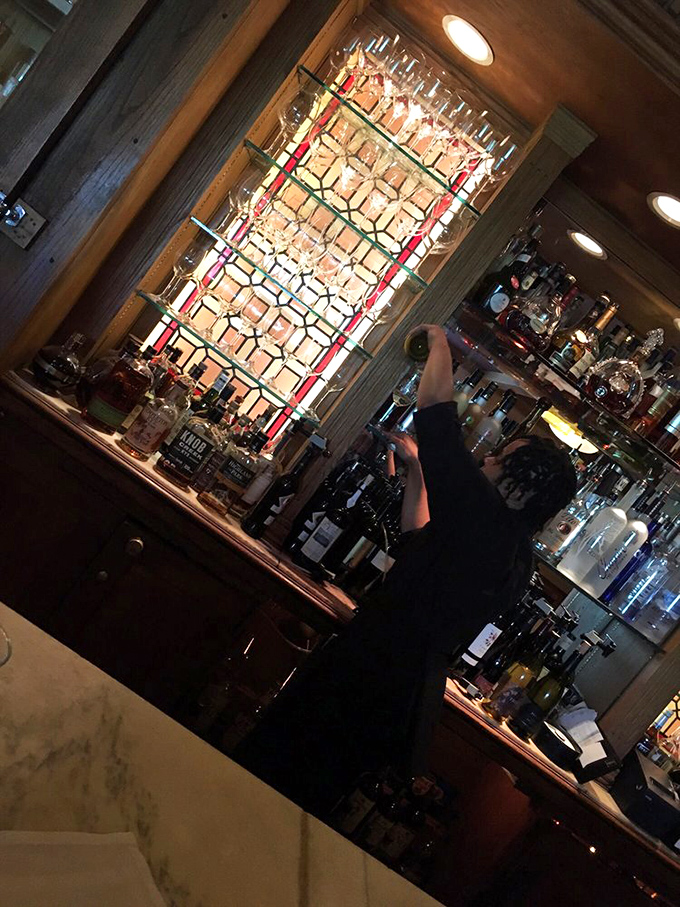 The stained glass glow behind the bar creates a warm halo effect &ndash; as if the spirits themselves are blessing your evening.