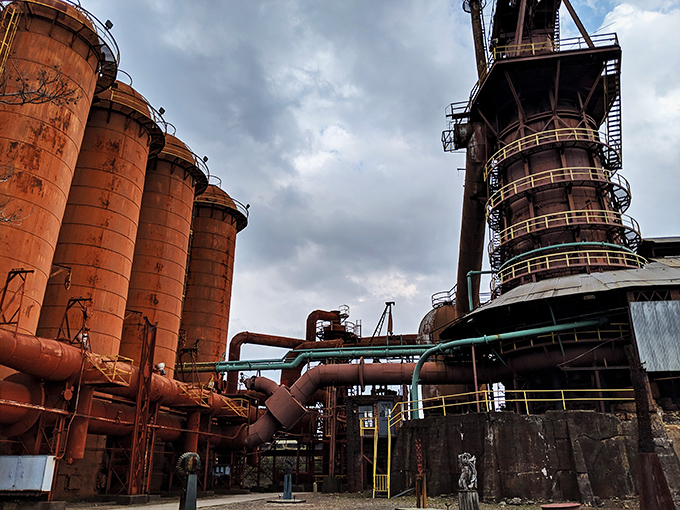The same pathway shown in image #13, where yellow safety railings guide modern visitors through a rust-colored cathedral of American industry.