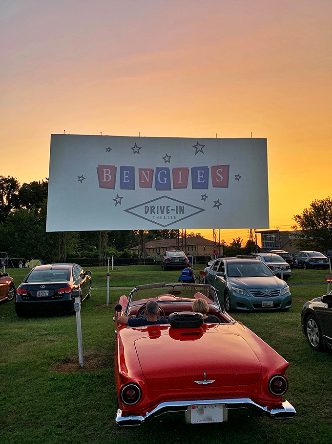 A classic convertible faces the screen at sunset, creating the perfect Norman Rockwell moment that sums up why drive-ins will never truly disappear.