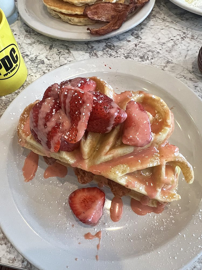 Strawberry waffles that make you question why people eat anything else for breakfast. The syrup river flowing into strawberry island is pure breakfast geography.