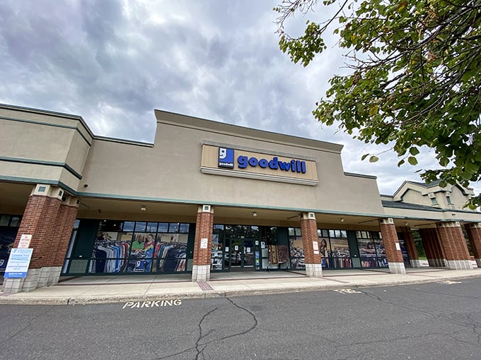 The blue Goodwill sign beckons like an old friend, promising treasures inside this Cheshire shopping center.