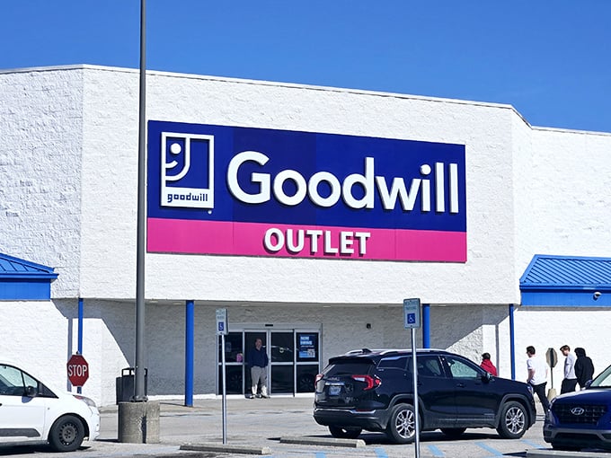 The blue and pink sign beckons like a siren song to bargain hunters. Goodwill Outlet: where shopping becomes an Olympic sport.