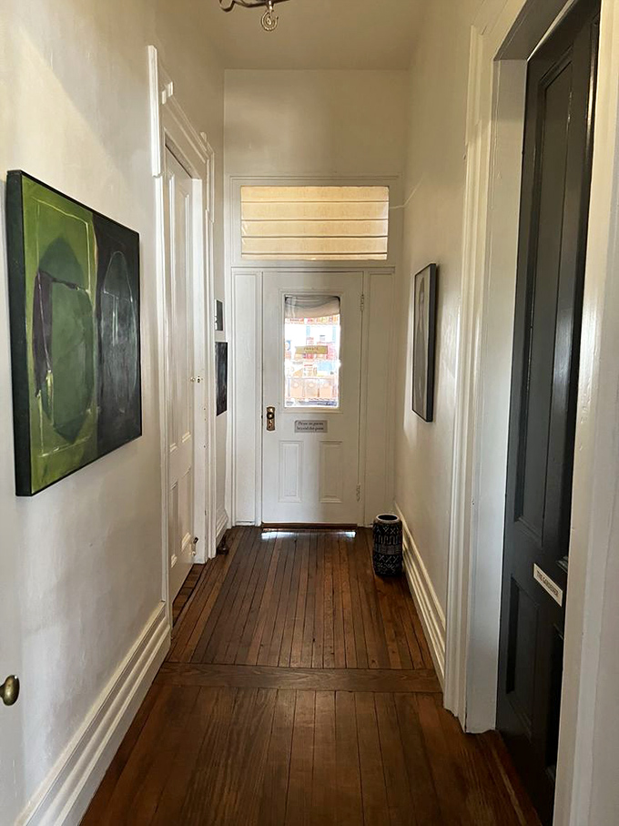 Historic heart pine floors lead the way through this elegant hallway, where original woodwork whispers tales of 19th century craftsmanship.