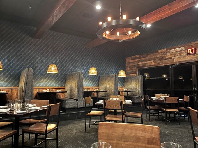 Textured blue walls, wooden accents, and high-backed booths create an atmosphere where both your steak and your secrets are safe.
