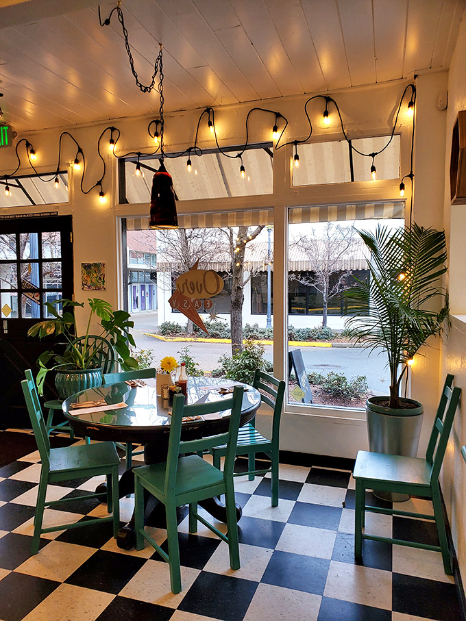 Sunlight streams through large windows, dancing across the iconic checkerboard floor while mint green chairs add a pop of personality to this breakfast sanctuary. 