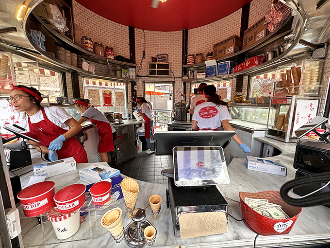 Inside the milk can, a well-choreographed ice cream ballet unfolds. Red-capped scoopers work their magic in this circular command center of frozen delight.