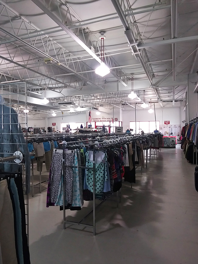 Beneath industrial ceilings, rows of carefully organized clothing create a secondhand department store where fashion finds await the patient explorer.