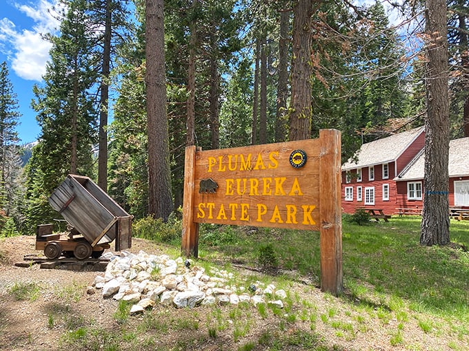 Welcome to California's best-kept secret. The park entrance sign stands beside a vintage mining cart, history and wilderness waiting just beyond.