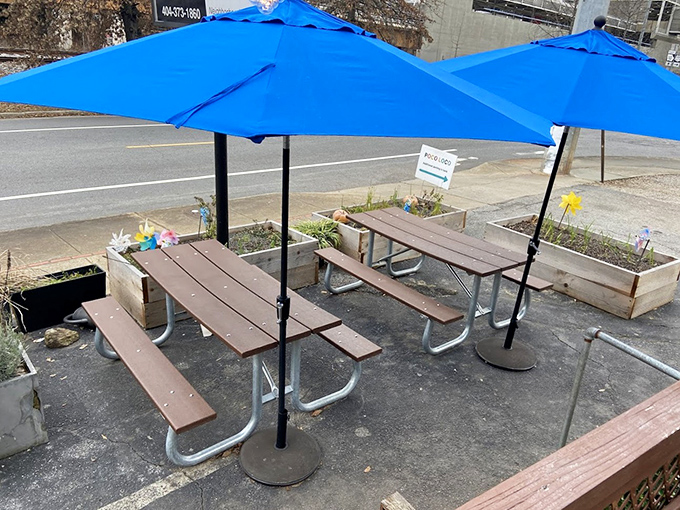 Simple picnic tables with bright blue umbrellas create an unpretentious outdoor dining space where strangers become friends over shared burrito revelations.