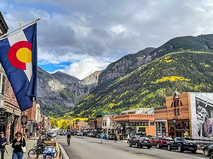 The Colorado flag waves proudly against a backdrop that makes screensavers jealous. Downtown Telluride's colorful buildings pop against the dramatic mountain canvas.