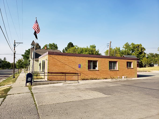 A modest brick post office with an American flag stands as a reminder that small-town America still delivers more than just mail&mdash;it delivers community.