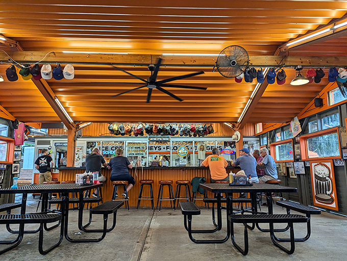 Baseball caps hang like trophies above diners, each representing a loyal customer who found their happy place at this no-frills counter.